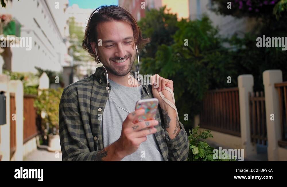 Smiling guy using Instagram swiping photos of friend and laughing of ...