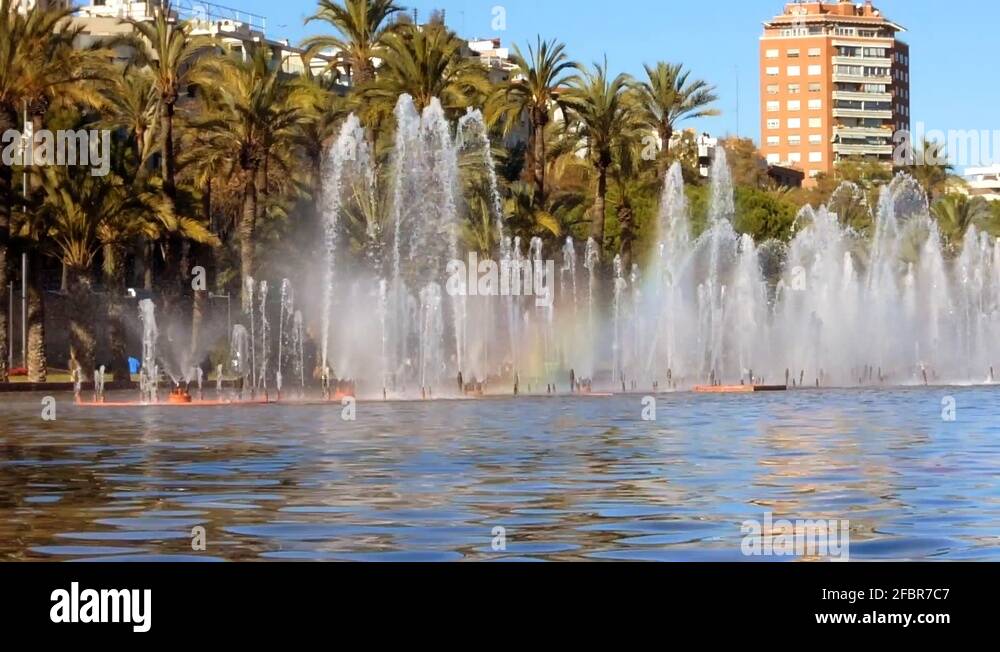 Beautiful spectacular water fountain with pond rainbow and palm trees ...