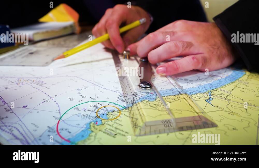 Yachts navigator using a parallel ruler and pencil while plotting a ...