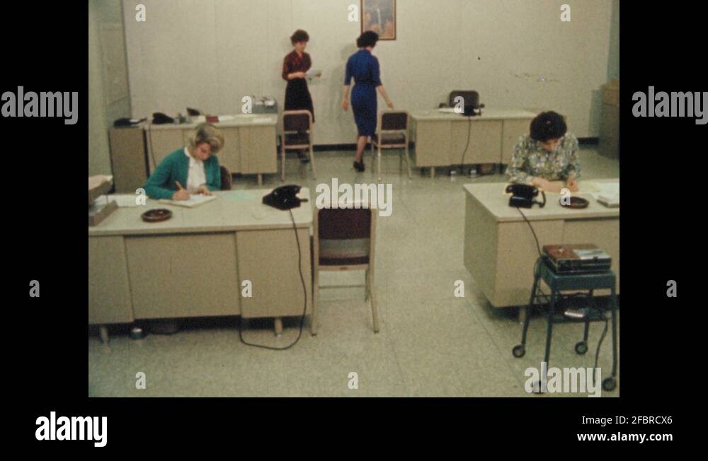 1960s: Woman work at desks in office. Women look at papers, check off ...