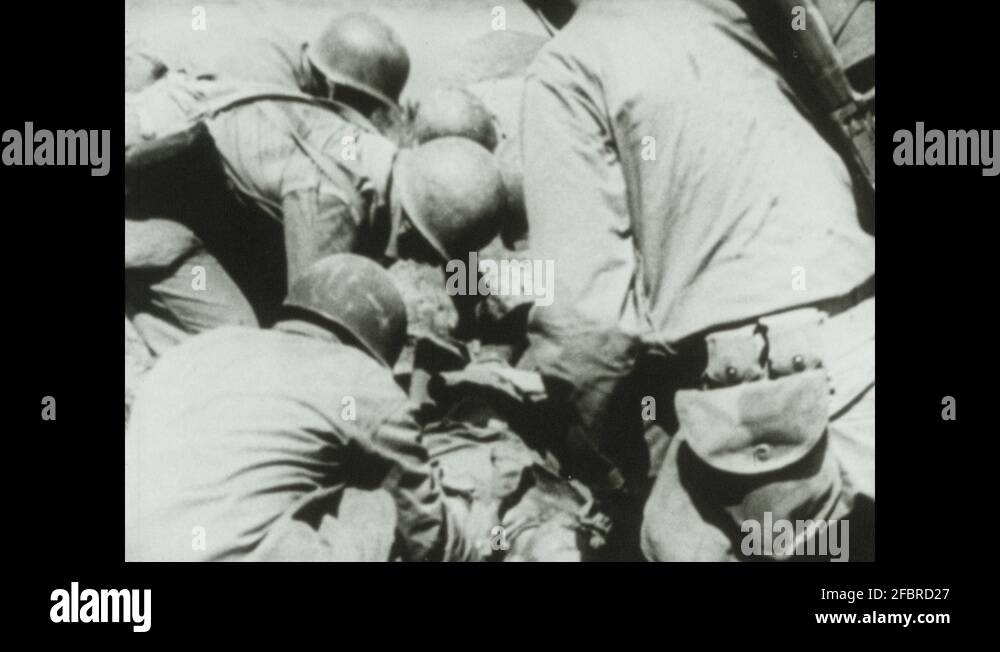 1940s: Wounded soldiers in field. Soldiers carry wounded man away. Bomb ...