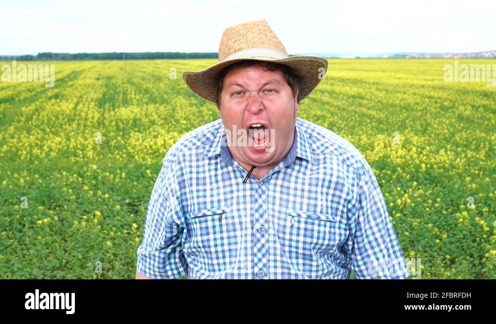 Farmer standing in field and screaming in horror or evil, in hat on a ...