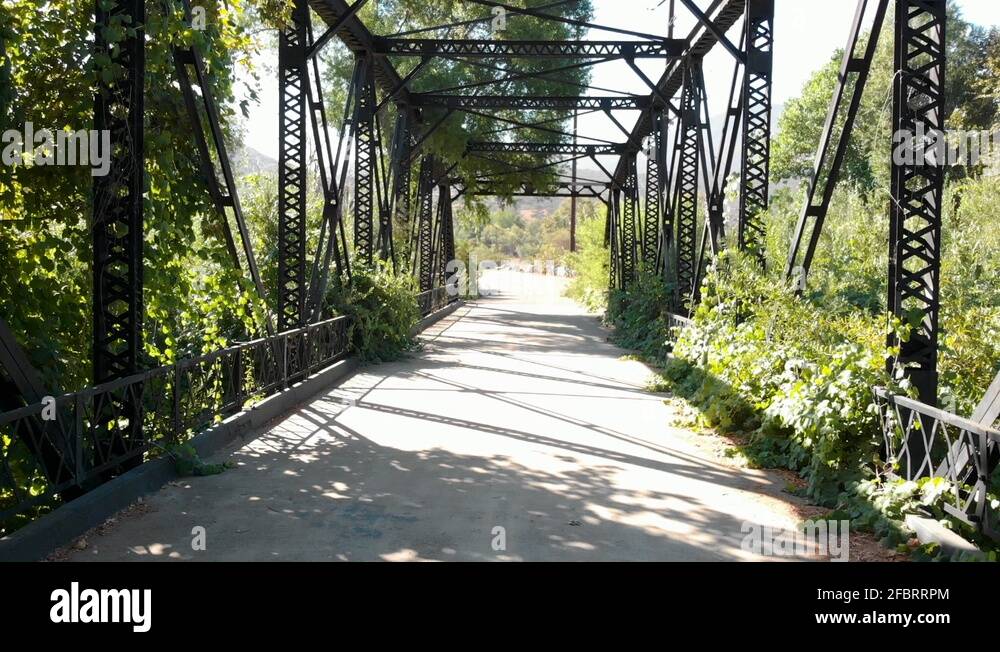 Pull out dolly shot across a steel overgrown bridge. Low flying drone ...