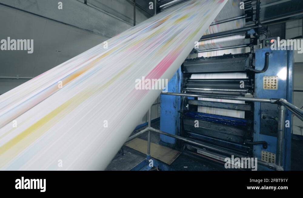 Uncut magazine pages are rolling through the printing press. Printing ...