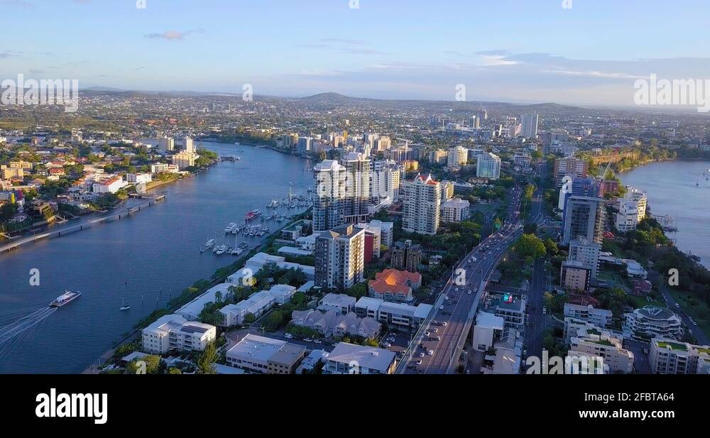 Panning aerial view of a Brisbane city with busy street and river curve ...