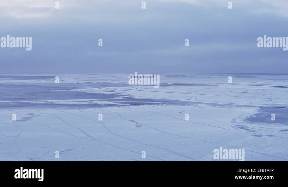 Cargo ship sailing in ice in a Frosty morning, filmed from passing ship ...