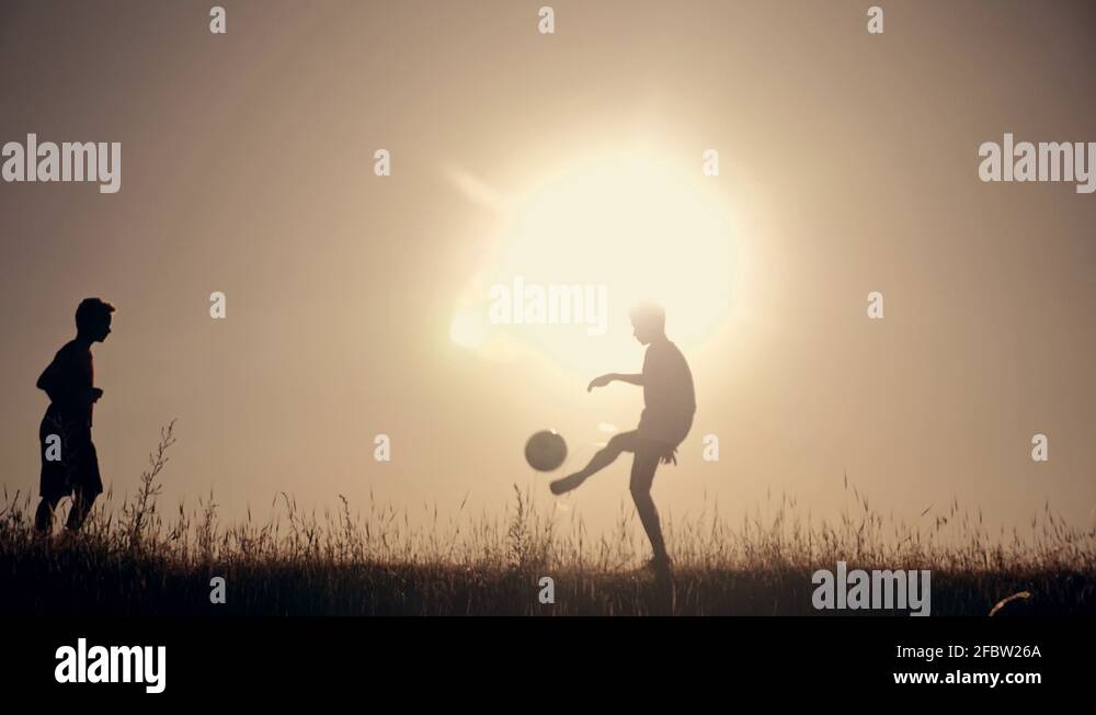 Two boys playing football at sunset. Silhouette of children playing ...