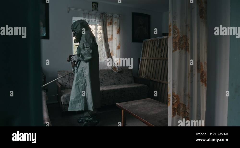 Unrecognizable male in hazmat suit and gas mask using Geiger counter on ...