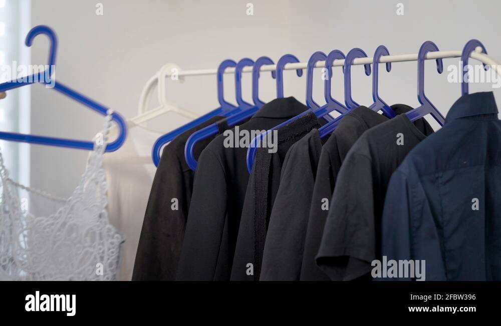 Rack full of black clothes. Woman hang different types of black clothes ...