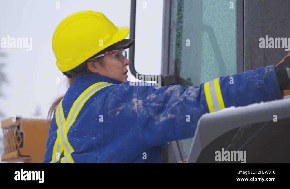 Female heavy equipment operator performs thorough inspection of loader ...