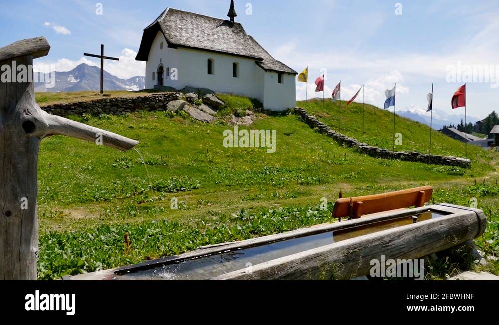 A small chapel on an elevation in the Swiss Alps with a water fountain ...