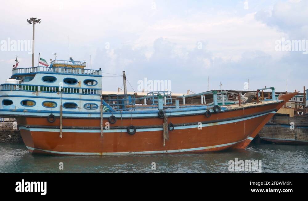 Tracking shot of Iranian launch Lenj fishing boats in a harbour strait ...