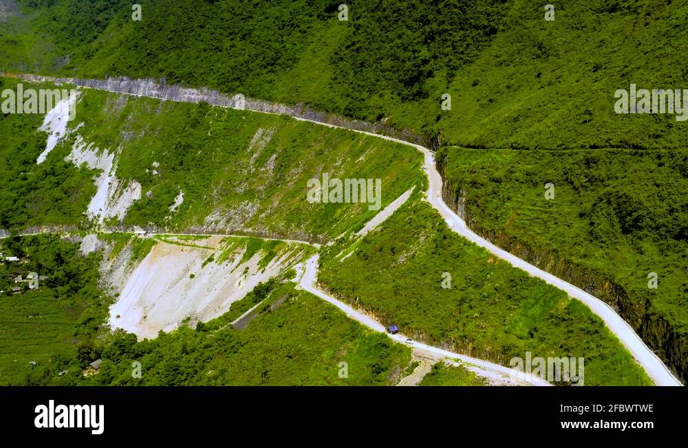 Green mountain side with winding roads and steep slopes. Aerial dolly ...