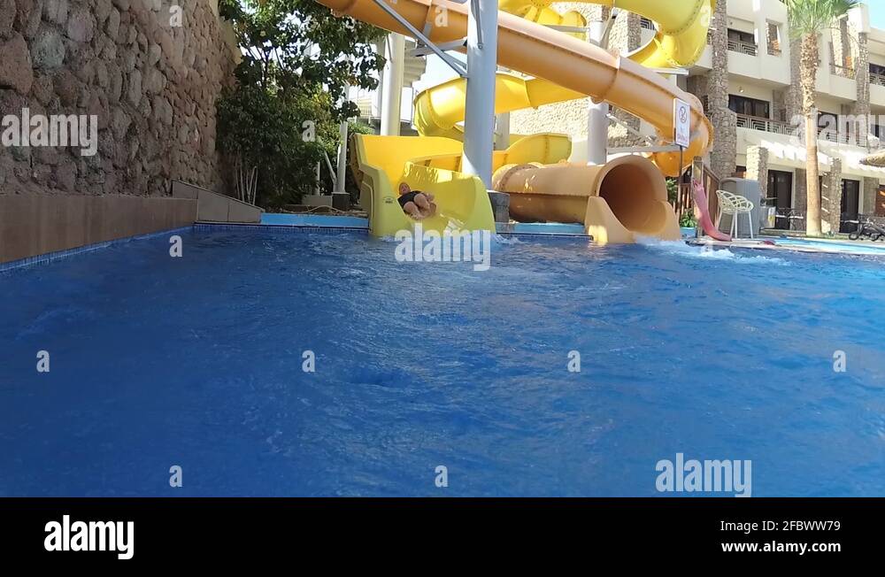 kid sliding down by water slide making splashing falling into swimming ...