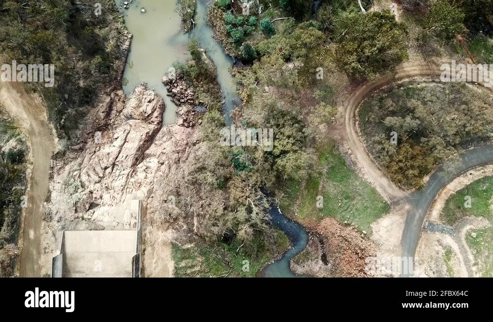 Aerial pan from top to bottom over the dam wall, spillway, water outlet ...