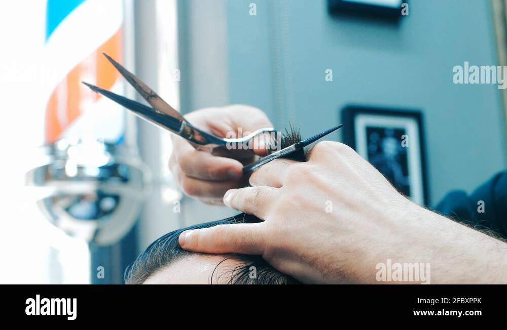 Barber using scissors and comb during making hairdo. Modern hair salon ...