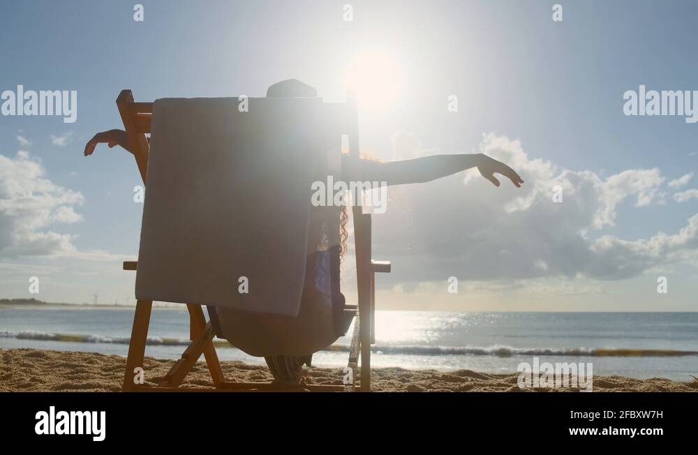 Back view of young beautiful woman sunbathe and relax on tropical beach ...