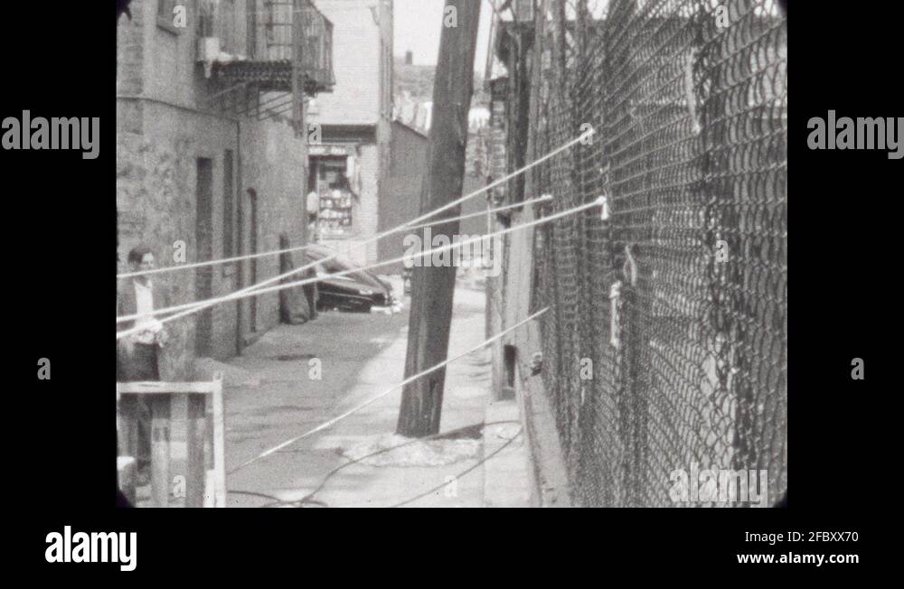 1920s: UNITED STATES: men stand in back alley. Washing lines on wall ...