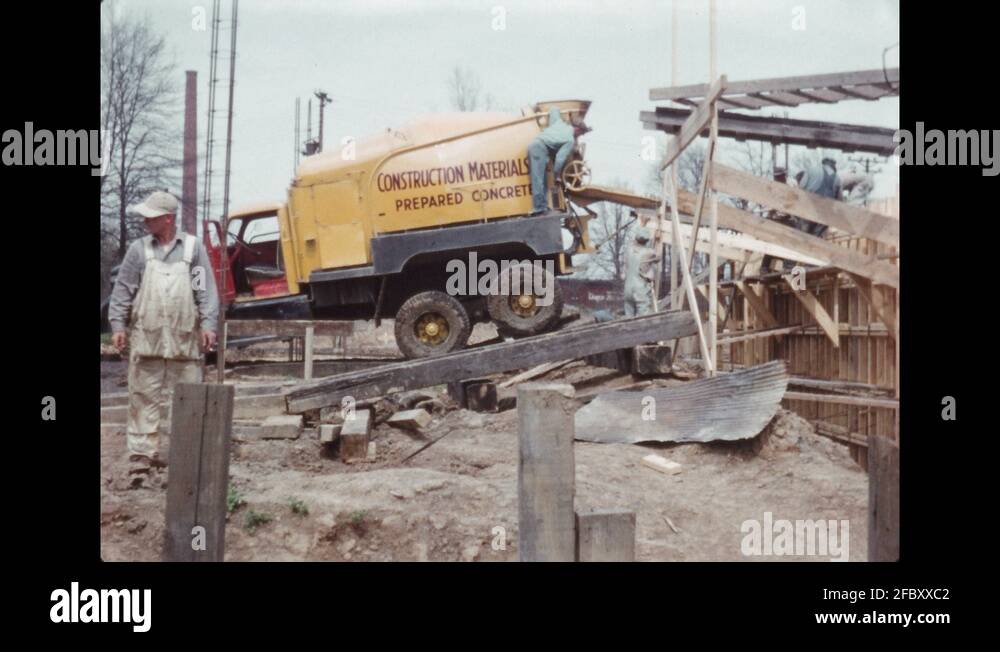 1950s: Workers on construction site with cement truck. Closer view of ...