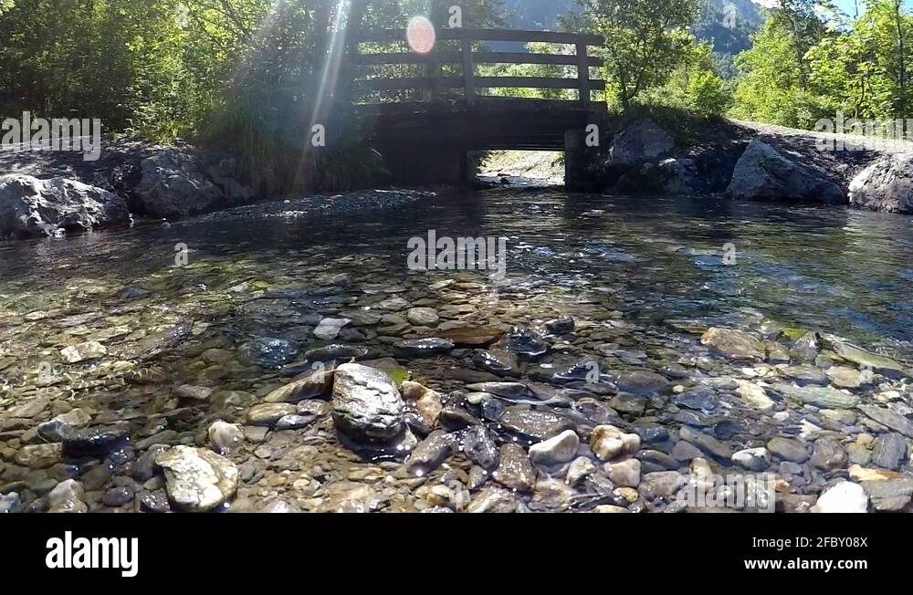 A stream that flows under a bridge. Lens flare from the sun Stock Video ...