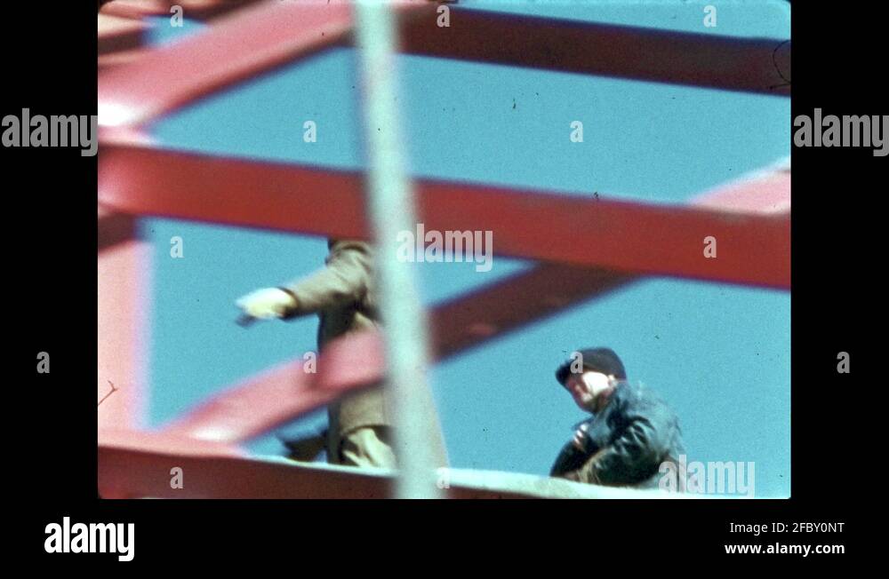 1950s: Low angle tracking shot, men on roof at construction site. Low ...