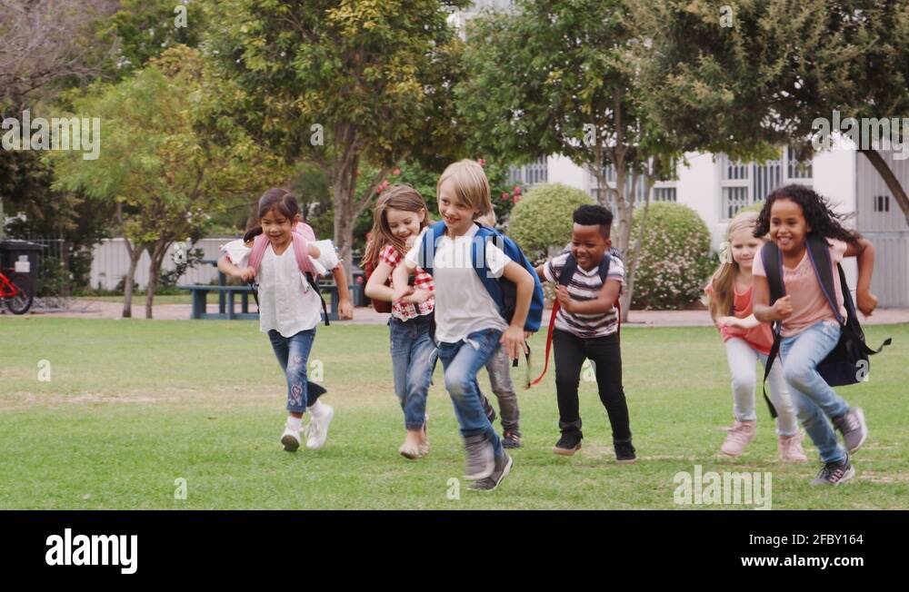 Excited Elementary School Pupils Wearing Uniform Running Across Field ...