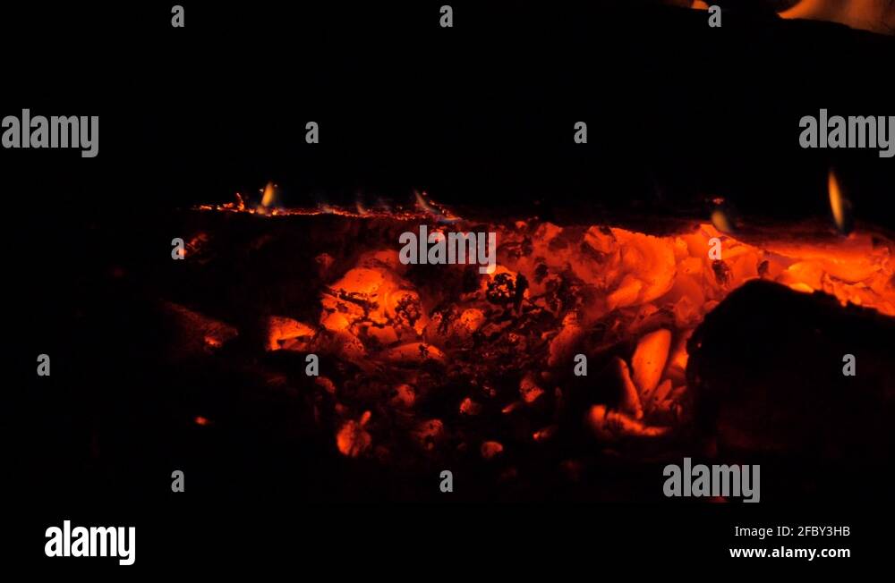 Close up of slowmotion air blowing ash and embers around a bonfire in ...