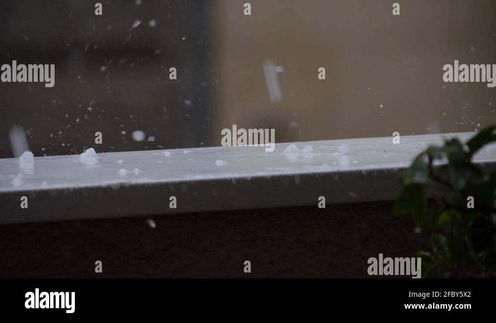 Hail stones falling and splashing on a balcony railing during a storm ...