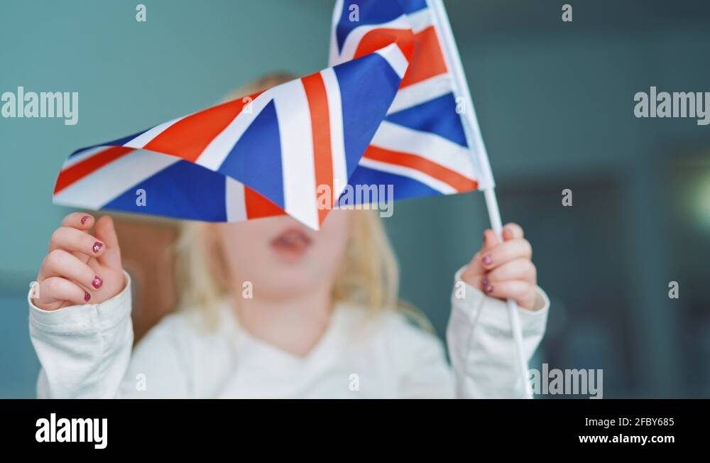 Cute little girl playing with British flag. English flag with three red ...