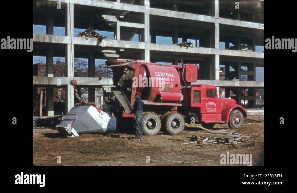 1950s: Truck on construction site, tilt up, crane lifts object onto ...