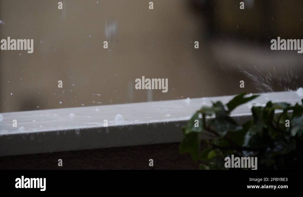 Ice drops of hail splashing on a balcony railing in downtown at summer ...
