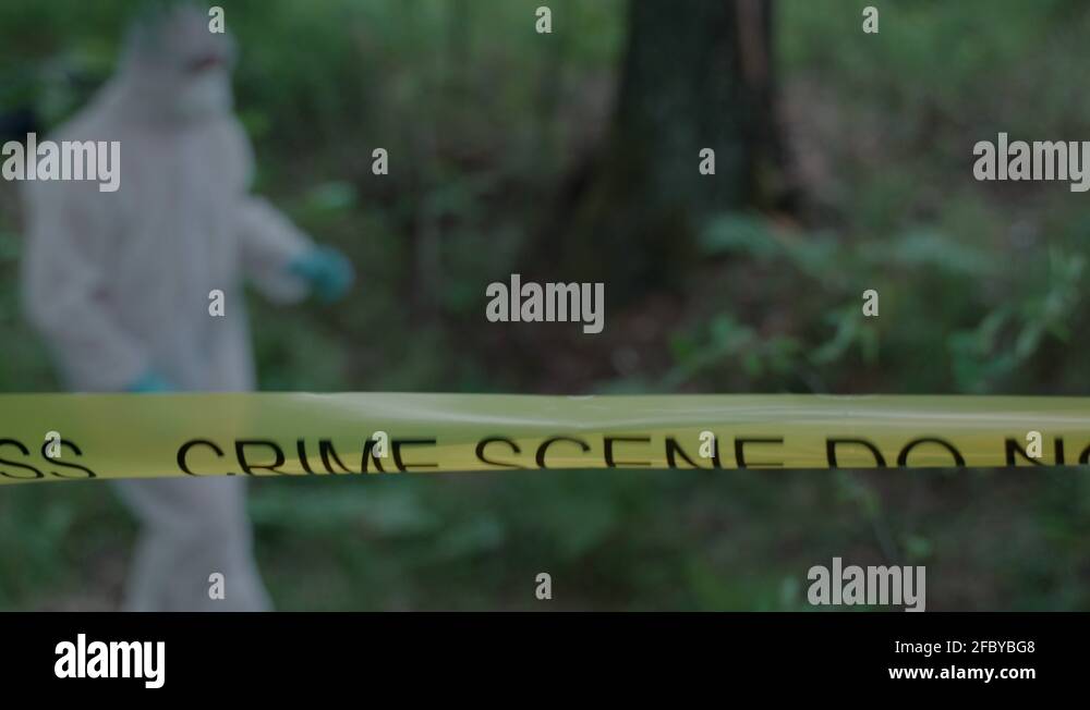Homicide police in protective suit collecting evidence behind crime ...