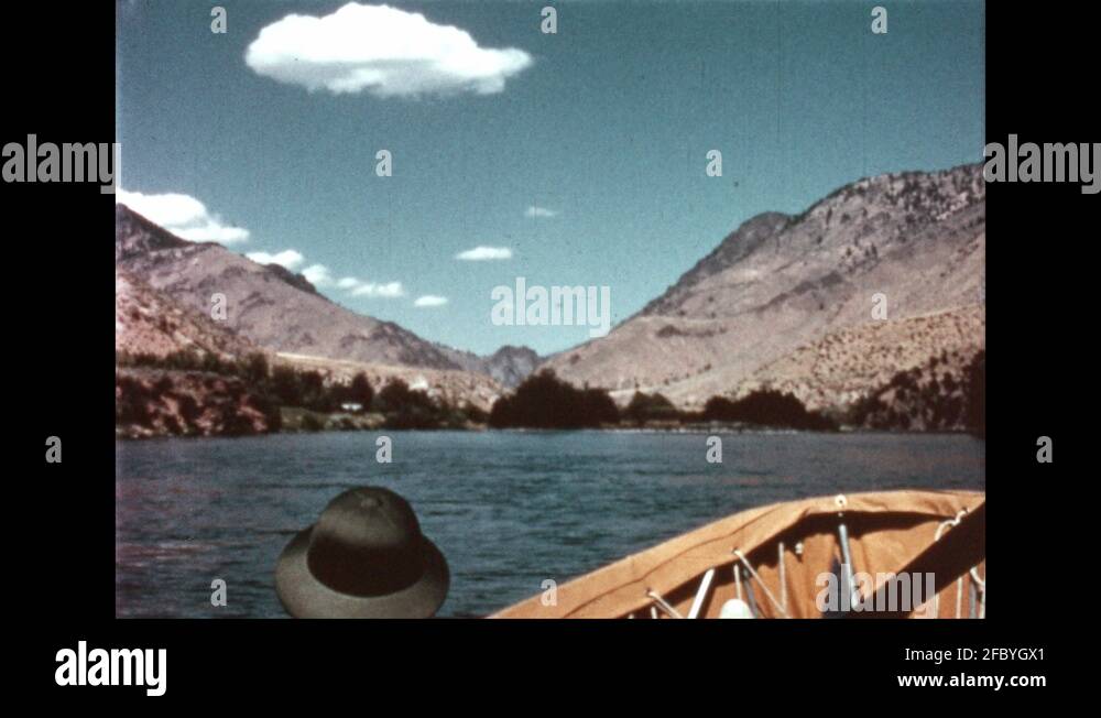 1950s: a boat floating down a river in front of mountains before ...
