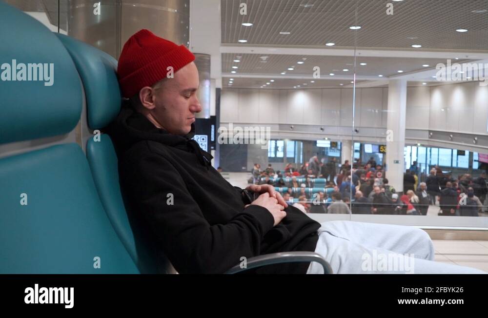 Handsome tired young man sleeping in airport terminal. Long distance ...