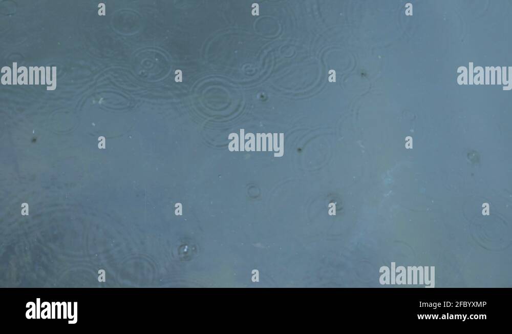 Drops of rain hitting the surface of water. Surface of ocean hit by ...