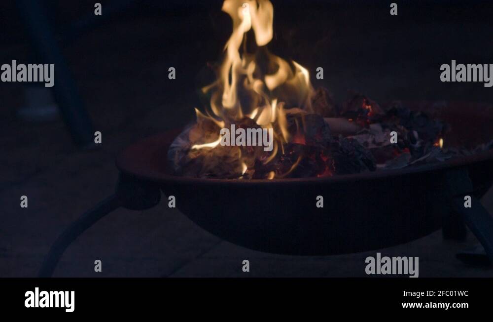 Newspaper being thrown into a fire, causing a small fireball explosion ...
