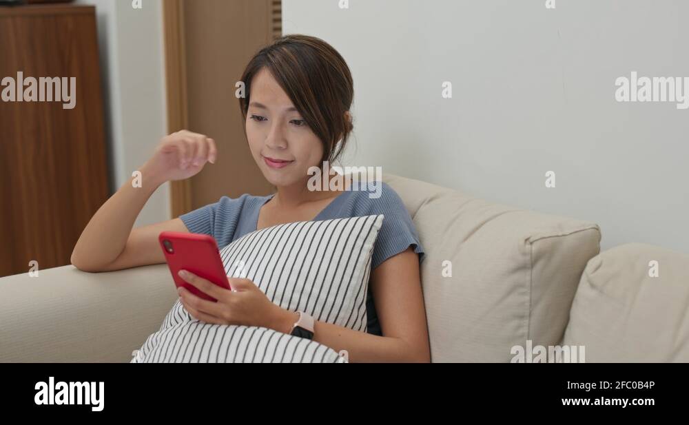 Woman use of mobile phone and sit on sofa at home Stock Video Footage ...