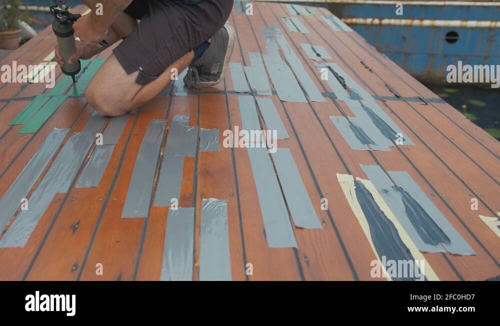 Young carpenter sealing roof planking flattening sika flex sealant ...