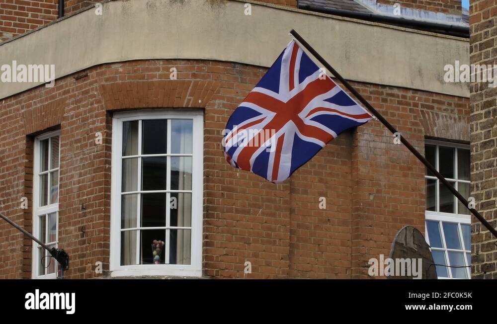 4K British Flag, Union Jack Waving in the Wind in front of a building ...