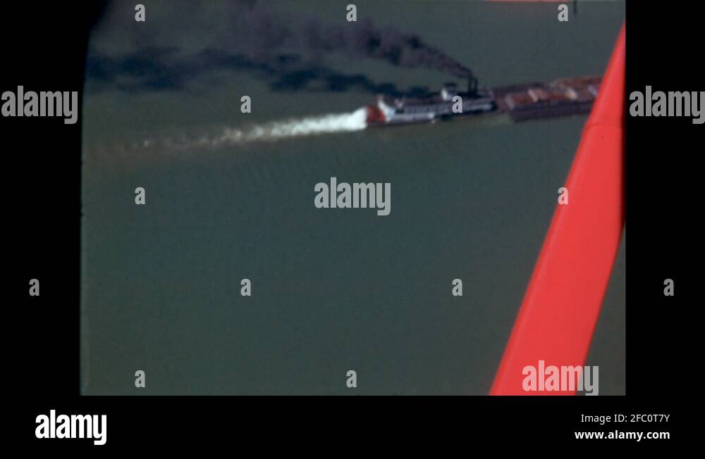 1940s: Tugboat pushes barges on lake from flying red plane, edge of ...