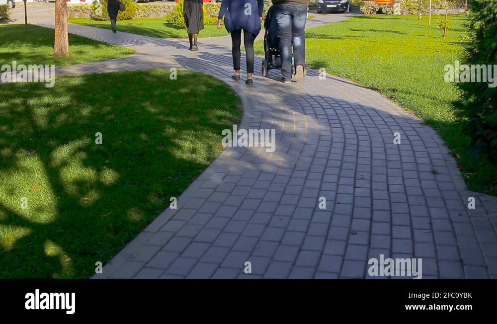 Footpath of paving slabs on which close-up feet of walking people in ...