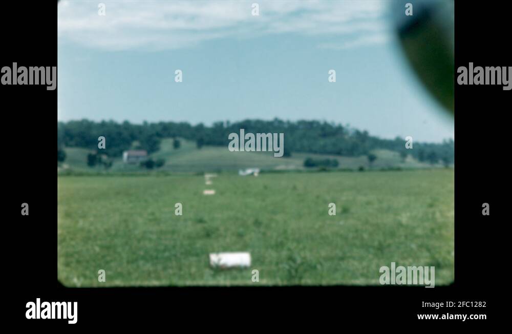 1940s: Small silver airplane rolls across grassy field in the distance ...