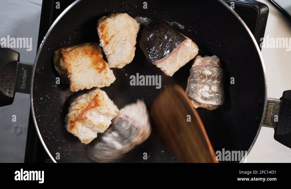 Chef uses his spatula to tip over fish bites.Process of cooking fish in ...