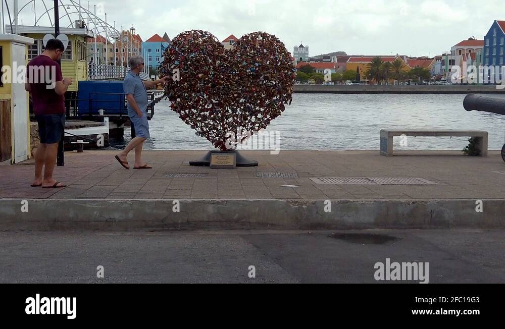 Man walking up to and touching Punda Love Heart in Curacao. The Love ...