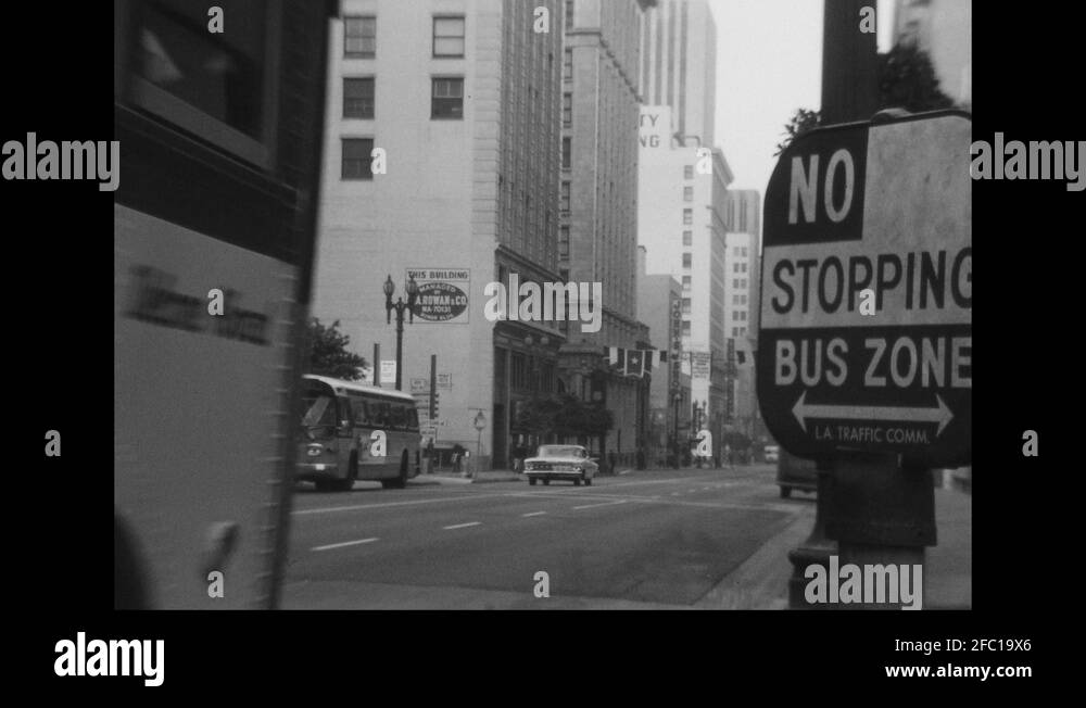 1960s: Bus pulls up to bus stop on busy city road. Man steps off bus ...