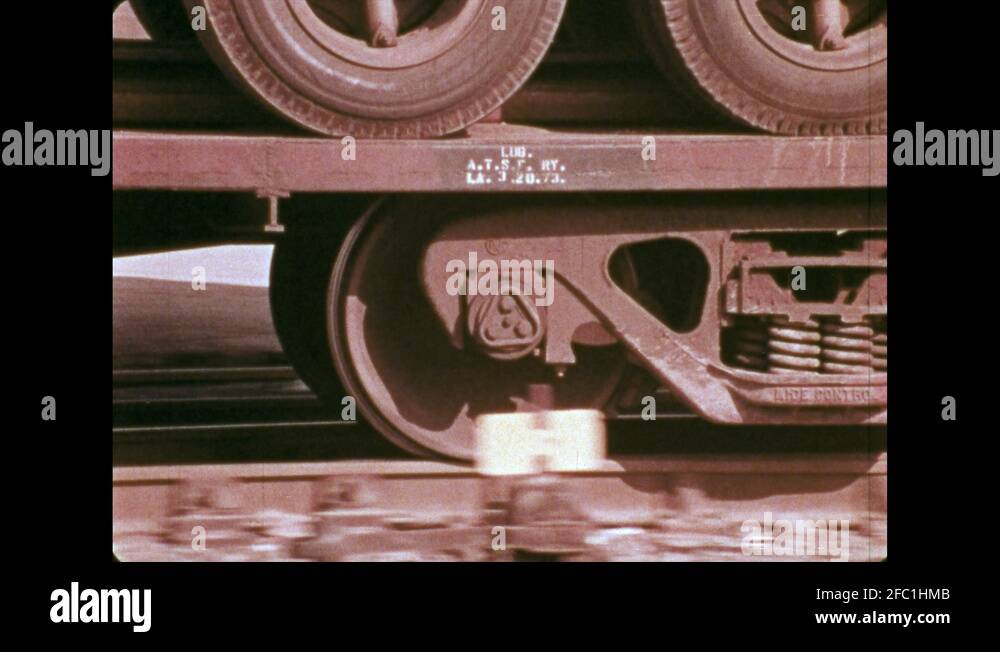 1970s: Train wheels roll on track. Train pulls line of shipping ...