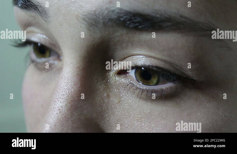 Beautiful girl is sad and crying. A tear rolls from the green eyes on ...