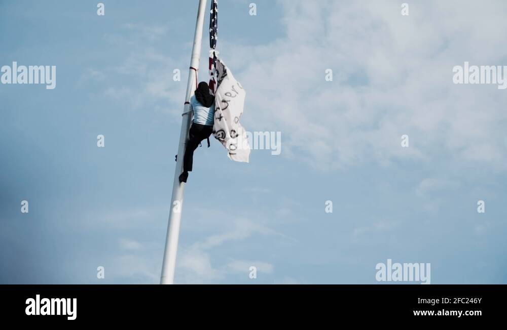 Man climbs flag pole to replace the American flag as hundreds of ...