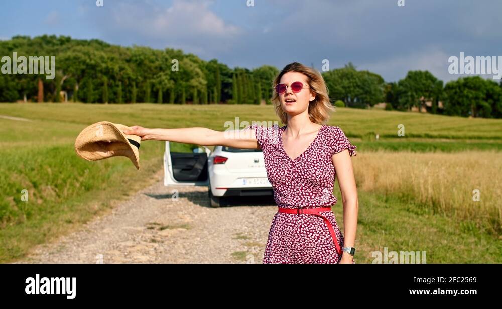 Attractive Blonde Girl Hitch Hiking On The Road In Countryside Car