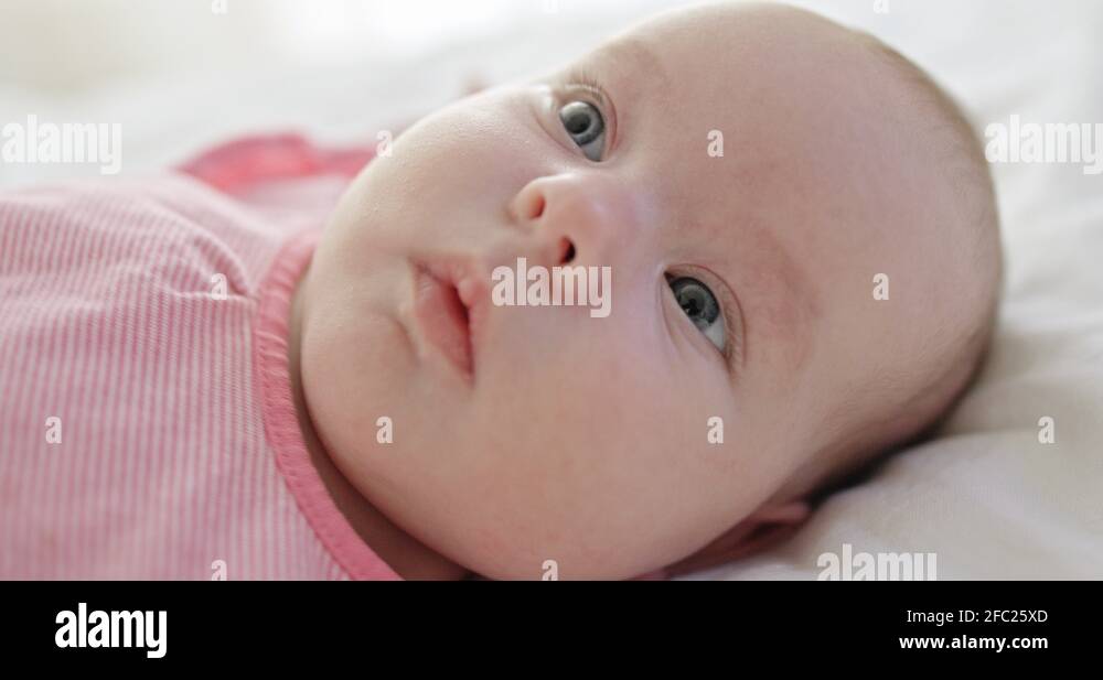Adorable chubby little baby girl with big blue eyes wriggling on her ...